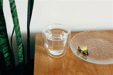 오메가 3 스피룰리나 엽록소 캡슐 나무 테이블에 물 한 잔 식이 보조 제 생물학적 활성 첨가제 아침 비타민 알약 건강 지원 공백 텍스트 0명에 대한 스톡 사진 및 기타