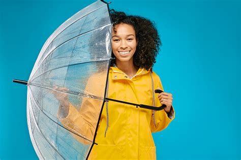 파란색 스튜디오 배경에 고립 된 투명한 우산이있는 노란색 방수 비옷을 입은 아프리카 계 미국인 여성 가을 시즌 개념 사람들에 대한 스톡 사진 및 기타 이미지 Istock