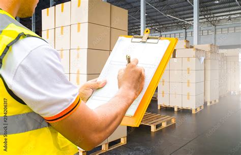 Warehouse Worker Hand Holding Clipboard Inspecting Checklist Of Goods Shipment At Distribution