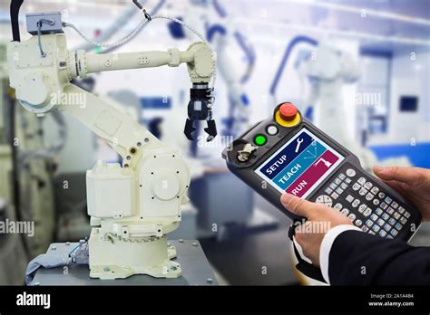 engineer with teach pendant device programming robot with robotic arm