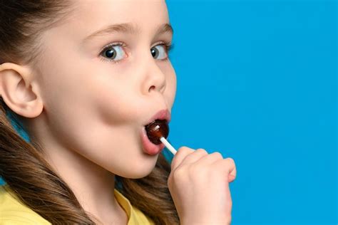Premium Photo On A Blue Background A Girl Licks A Round Lollipop Closeup