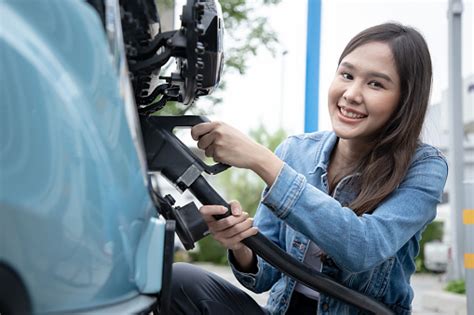 그녀의 차와 함께 Ev 충전소에서 Dcccs 유형 2 Ev 충전 커넥터를 들고 있는 아시아 여성 차량 충전을 위한 Ev 전기
