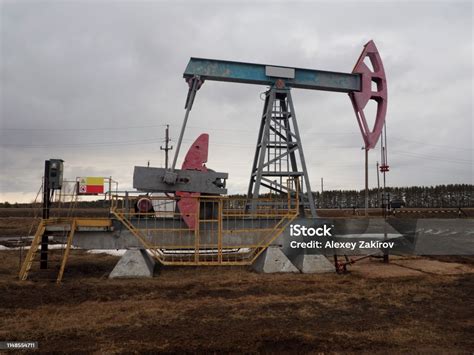 빔 펌핑 유닛은 숙제 오일 필드의 일몰입니다 석유 펌프 오일 장비 에너지 산업 기계 펌프가 우물에 설치 된 펌핑 장치 오일 분야의 장비 강철에 대한 스톡 사진 및 기타