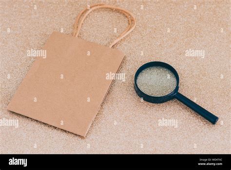 shopping bag and magnifying glass analyzing it on golden glitter background customer spending