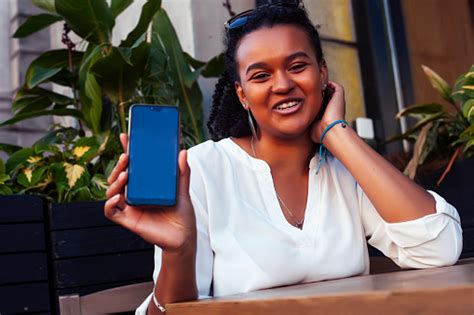 젊은 예쁜 아프리카 소녀 포즈 명랑 한 카페 야외 라이프 스타일 사람들 개념 Brand Name Smart Phone에 대한 스톡 사진 및 기타 이미지 Brand