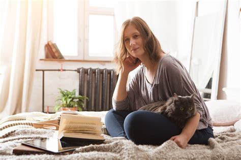 집에서 침대에 누워 있는 고양이 함께 젊은 여자 겨울 또는을 주말 개념입니다 책을 읽고 하 고 침실에서 차를 마시는 여자 가정용