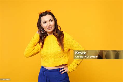 스웨터에 호기심 젊은 여자의 초상화 블루 바지 심장 안경 서 옆으로 보이는 노란 주황색 배경에 고립 사람들은 진심으로 감정 라이프 스타일 개념입니다 복사 공간을 모의 합니다