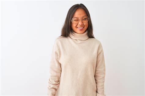 거북이 스웨터와 안경을 착용한 젊은 중국 여성이 섹시한 표정과 명랑하고 행복한 얼굴로 카메라를 바라보고 있는 고립된 흰색 배경 윙크 겨울에 대한 스톡 사진 및 기타 이미지