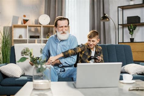 Ni O En Edad Escolar Sonriente Muestra Un Nuevo Juego Para Su Adorable Abuelo Sonriente Foto