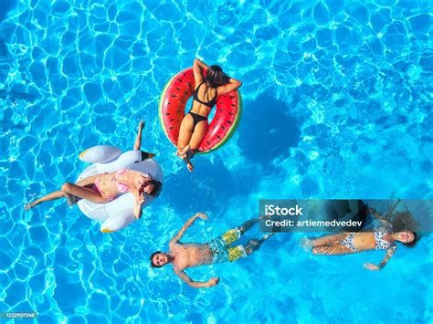 풍선 플라밍고 백조 매트리스와 수영장에서 파티를 하는 친구의 공중 화창한 날에는 고급 리조트에서 행복한 젊은이들이 휴식을 취합니다 위에서 볼 수 있습니다 태양에서 일광욕