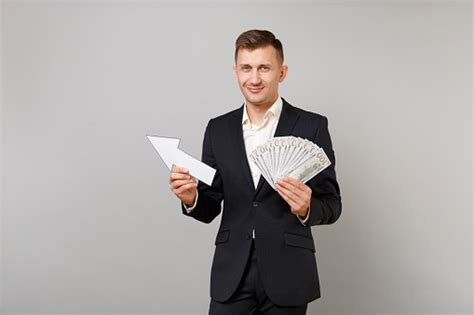 젊은 사업가 달러 지폐 현금 돈 회색 배경에 고립의 많은 무리를 누르고 화살표와 함께 옆으로 보여주는 미소 성과 경력 부 비즈니스 개념입니다 복사 공간을 비웃는 다 검은색에