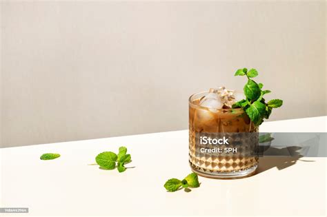 보드카 커피 리큐어 민트 슈납스 베이지색 배경에 크림과 얼음 단단한 빛 그림자 패턴 복사 공간이 있는 민트 화이트 러시아 알코올