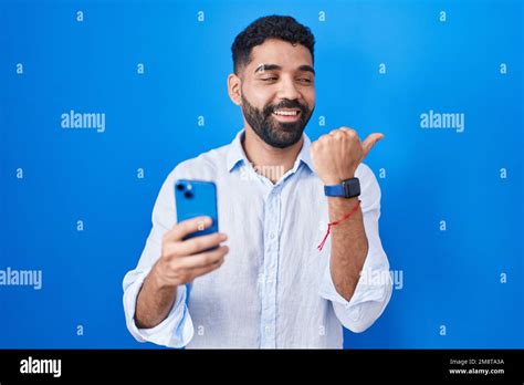 Hispanic Man With Beard Using Smartphone Typing Message Smiling With