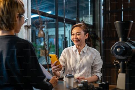 스마트폰을 스캔하는 바코드를 사용하여 비접촉식 결제를 하는 현대 아시아 여성은 커피숍에서 커피를 확인합니다 전자 모바일 뱅킹