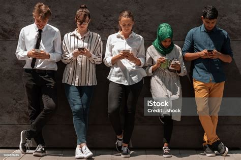 외부 검은 벽 앞에서 직장에서 커피 휴식 중에 휴대 전화를 사용하는 캐주얼 비즈니스 사람들의 다민족 그룹 20 24세에 대한 스톡 사진 및 기타 이미지 Istock