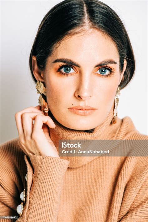 어두운 머리와 파란 눈을 가진 아름 다운 젊은 여자의 스튜디오 샷 갈색 메이크업과 터틀 넥 풀 오버를 입고 귀걸이에 대한 스톡 사진 및 기타 이미지 Istock