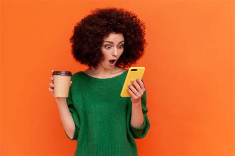 녹색 캐주얼 스웨터를 입은 아프로 헤어스타일을 손에 들고 커피를 마시고 충격적인 소식을 낭독한 놀란 여성 놀라움에 대한 스톡 사진 및 기타 이미지 Istock