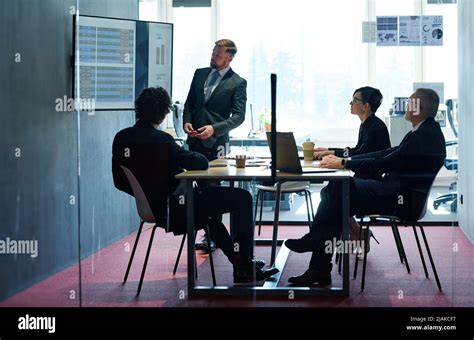 Project Manager Pointing At Desktop Presenting Statistical Data Briefing Diverse Group Of