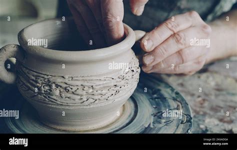 Close Up Shot Of Muddy Male Potters Hands Shaping And Fixing Ears Of