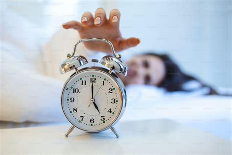 Woman Lying In Bed Turning Off An Alarm Clock In The Morning At 5am Hand Turns Off The Alarm