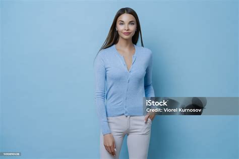 귀여운 열정적 인 여성은 슬림 한 그림을 가지고 캐주얼 점퍼와 흰색 청바지를 입고 주머니에 손을 유지 자신감 스탠드 친구와 함께