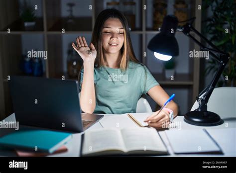 teenager girl doing homework at home late at night waiving saying hello