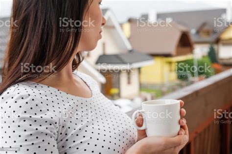 발코니에 서 있는 흰색 차 또는 커피 한 잔을 들고 있는 폴카 도트 티셔츠를 입은 젊은 여성 시골에서 아침 휴식의 개념 T 셔츠에 대한 스톡 사진 및 기타 이미지 Istock