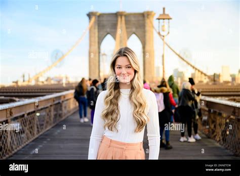 A Young Blonde Woman Stands On A Crowded Brooklyn Bridge In The New