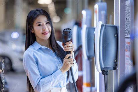 Babe Asian Woman Holding The CCS EV Charging Connector At EV Charging Station In Department