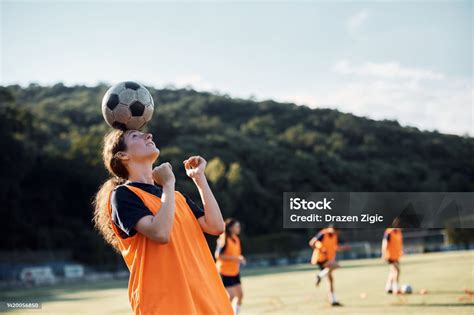 숙련 된 여성 축구 선수가 경기장에서 머리에 공을 균형 잡습니다 축구에 대한 스톡 사진 및 기타 이미지 축구 헤딩 여자