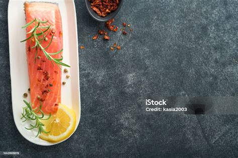 연어 물고기 조각입니다 대리석 보드에 신선한 생 연어 생선 조각은 검은 배경에 허브와 레몬이 있습니다 해산물 또는 메뉴 개념 평면도 건강에 좋지 않은 음식에 대한 스톡 사진
