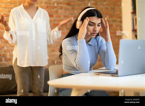 Problems Between Generations Concept Teen Girl Wearing Headphones And Touching Head While Her