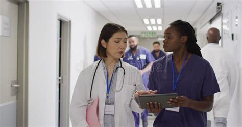 Video Of Two Diverse Female Doctors Walking In Busy Hospital Corridor