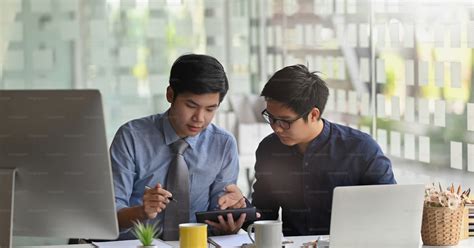 현대 사무실 위의 긴 작업 책상에 앉아 컴퓨터 노트북과 태블릿으로 함께 일하는 두 명의 똑똑한 남자의 사진 사진 Unsplash의 태국 이미지