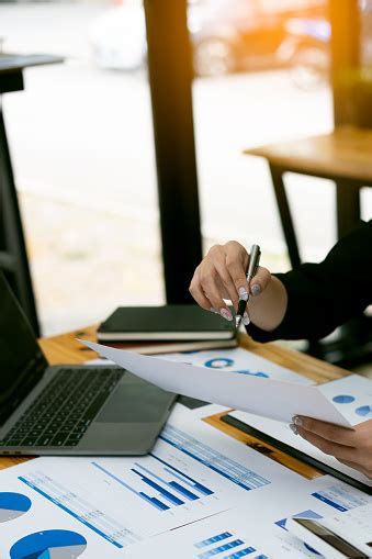 사업가는 펜을 들고 차트 그래프로 작업하고 비즈니스 전략을 분석합니다 노트북이 책상 세로보기에 앉아있는 재무 통계 National Hispanic Prayer