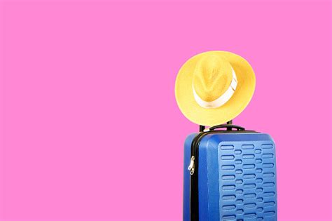 여자 밀 짚 모자에 매달려 단일 블루 플라스틱 하드 쉘 수하물 망원경 핸들 확장 가방 하나입니다 여행 혼자 개념입니다 밝은 분홍색 벽 배경 텍스트 복사 공간 닫습니다 가방에