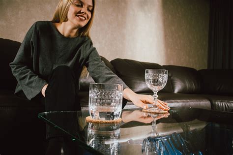 젊은 백인 금발 소녀 사용자 지정 V8 자동차 엔진 테이블 럭셔리 인테리어에 위스키의 유리를 가진 소파에 앉아 패션 사진과 아름 다운 미소 V8에 대한 스톡 사진 및 기타