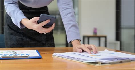 스마트폰을 들고 사무실 책상에서 재무 보고서를 확인하는 자른 사업가 사진 Unsplash의 태국 이미지