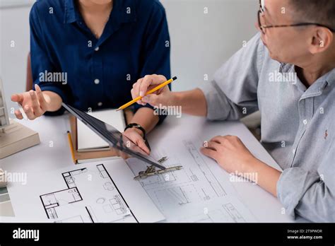 Two Architects Checking Blueprint On Tablet And Analyzing About Construction Of Building Project