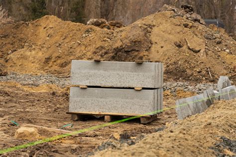 건설 현장에서 작업자들은 중장비와 흙으로 둘러싸인 자갈 표면에 콘크리트 블록을 정리하느라 바쁩니다 0명에 대한 스톡 사진 및 기타 이미지 Istock