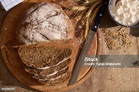 나무 판자에 부스러기가있는 신선한 빵 밀 스파이크 렛 및 삼베 식탁보에 흩어져있는 시리얼 곡물을 볼 수 있습니다 건강한 식생활에