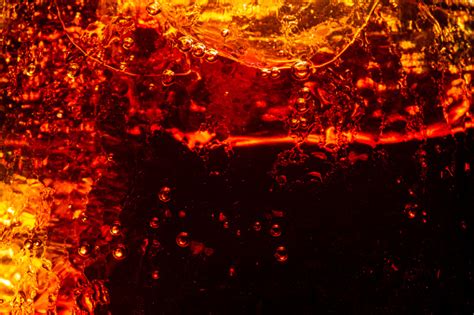 매크로 콜라 배경 어두운 콜라 배경에 있는 얼음 조각의 보기를 닫습니다 차가운 여름 음료의 질감은 유리벽에 거품과 매크로 거품이 있습니다 거품이 일거나 표면 위로 떠오르는