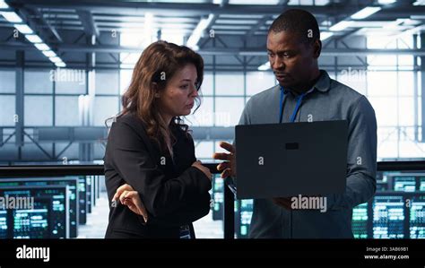 Developers In Data Center Workspace Coding On Laptop Analyzing Metrics Optimizing Storage