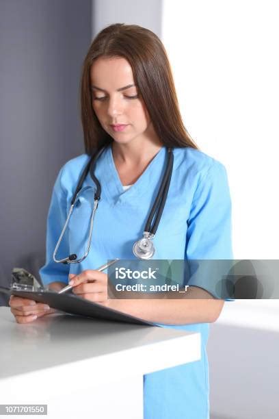 직장에서 의사 여자입니다 클리닉 또는 응급 병원 리셉션 데스크 근처에 서 있는 동안 의료 양식을 작성 여성 의사의 초상화 의학 및 건강 관리 개념 병원에 대한 스톡 사진 및