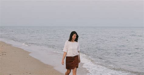 평온한 힙스터 여자는 저녁에 파도가 치는 모래 사장을 맨발로 걷고 고요한 순간을 즐기고 있습니다 캐주얼한 젊은 여성이 리조트의 해변에서 휴식을 취하고 있다 마음 챙김