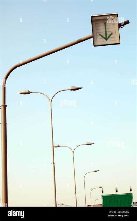 An Overhead Road Sign Followed By A Row Of Street Lights With Another