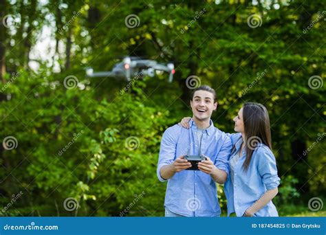 Young Couple Navigating A Flying Drone With Remote Control Man And