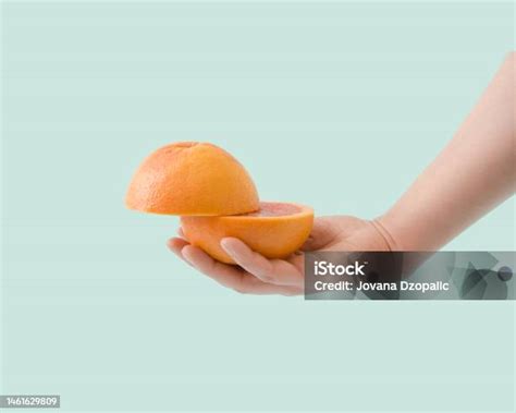 여자 손은 청록색 녹색 파란색 배경에 그녀의 손에 빨간 자몽의 두 반쪽을 들고 있습니다 여름 건강 과일 개념입니다 감귤류 과일에 대한 스톡 사진 및 기타 이미지 Istock