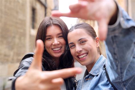 Same Sex Female Couple Pose For Photo Making Shape Of Frame With Hands As They Visit City