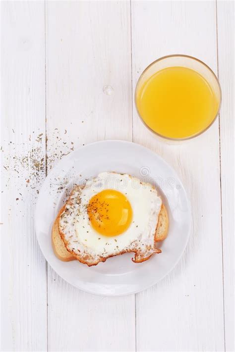 Fried Eggs On A Slice Of White Bread And A Glass Of Orange Juice Stock